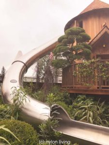 A free standing tree house with a tree house slide